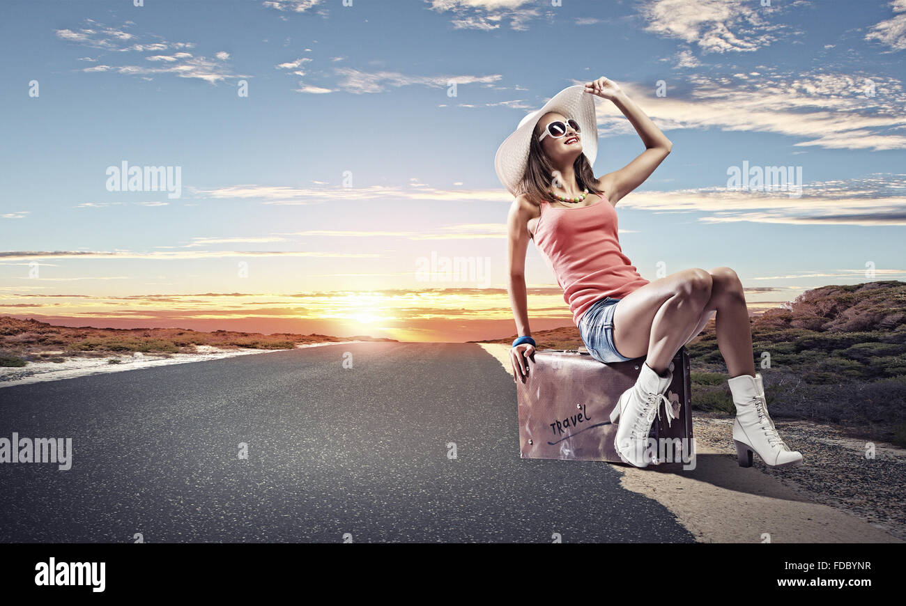 Young pretty girl traveler sitting on suitcase aside of road Stock ...