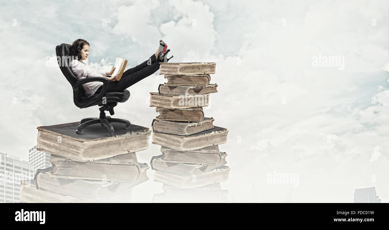 Young businesswoman sitting in chair and reading book Stock Photo - Alamy