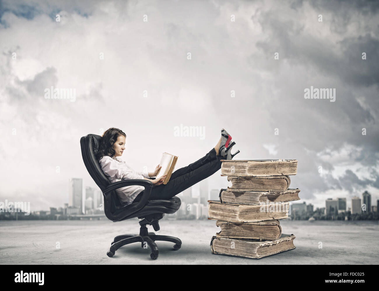 Young businesswoman sitting in chair and reading book Stock Photo - Alamy