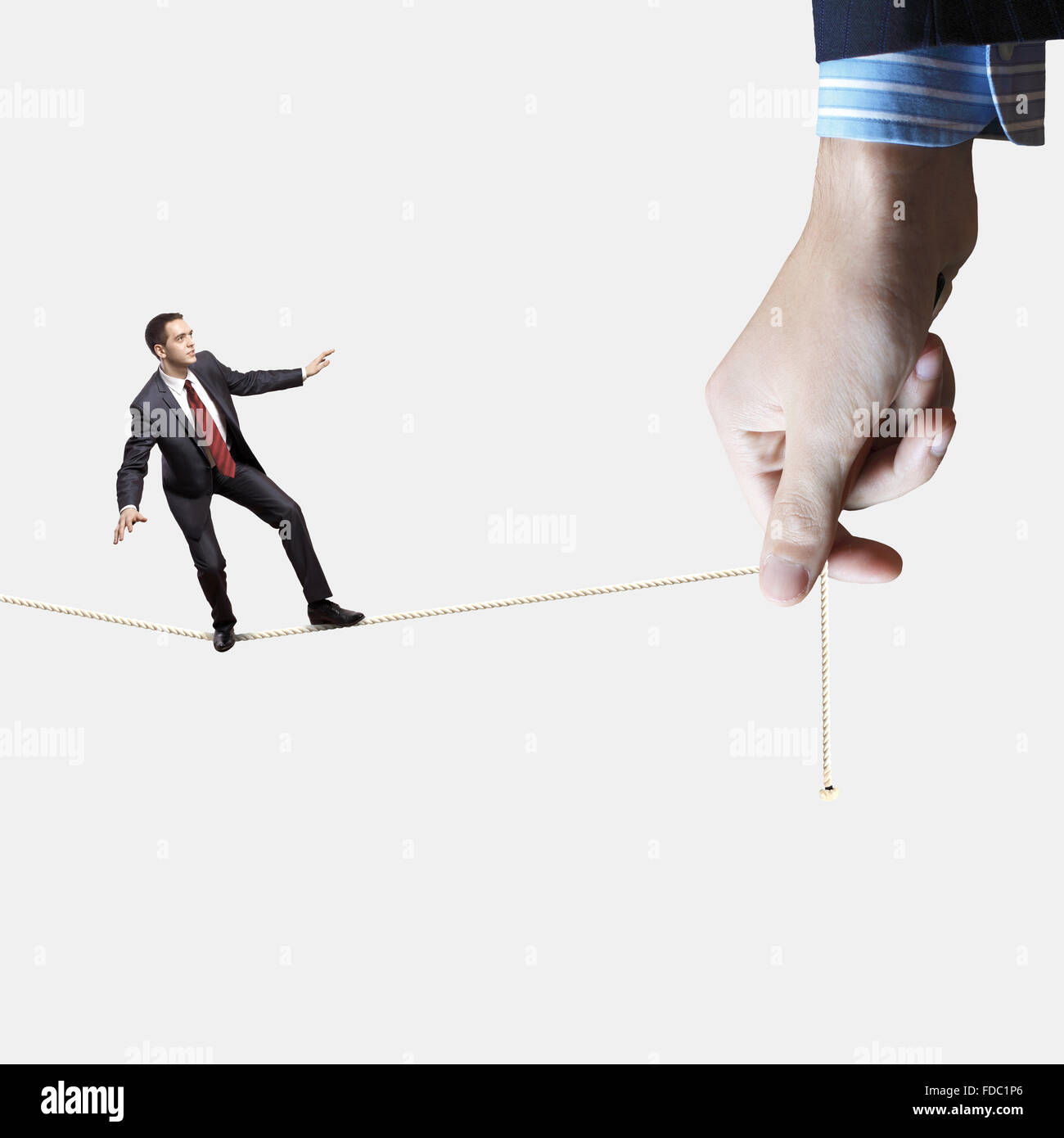 Young businessman balancing on rope controlled by male hand Stock Photo ...