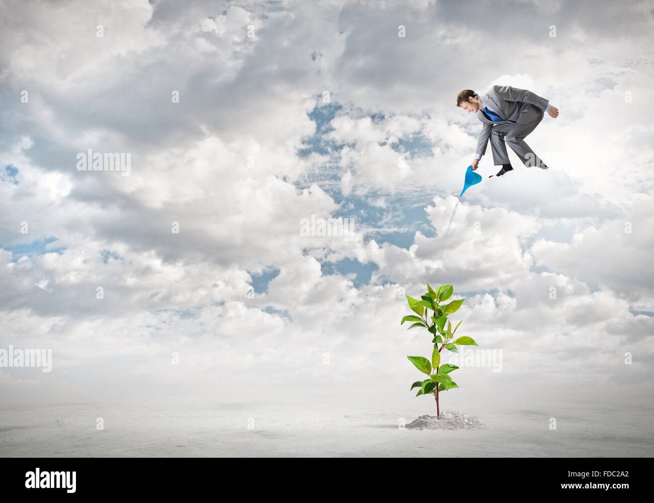 Young businessman standing on cloud and watering sprout Stock Photo - Alamy