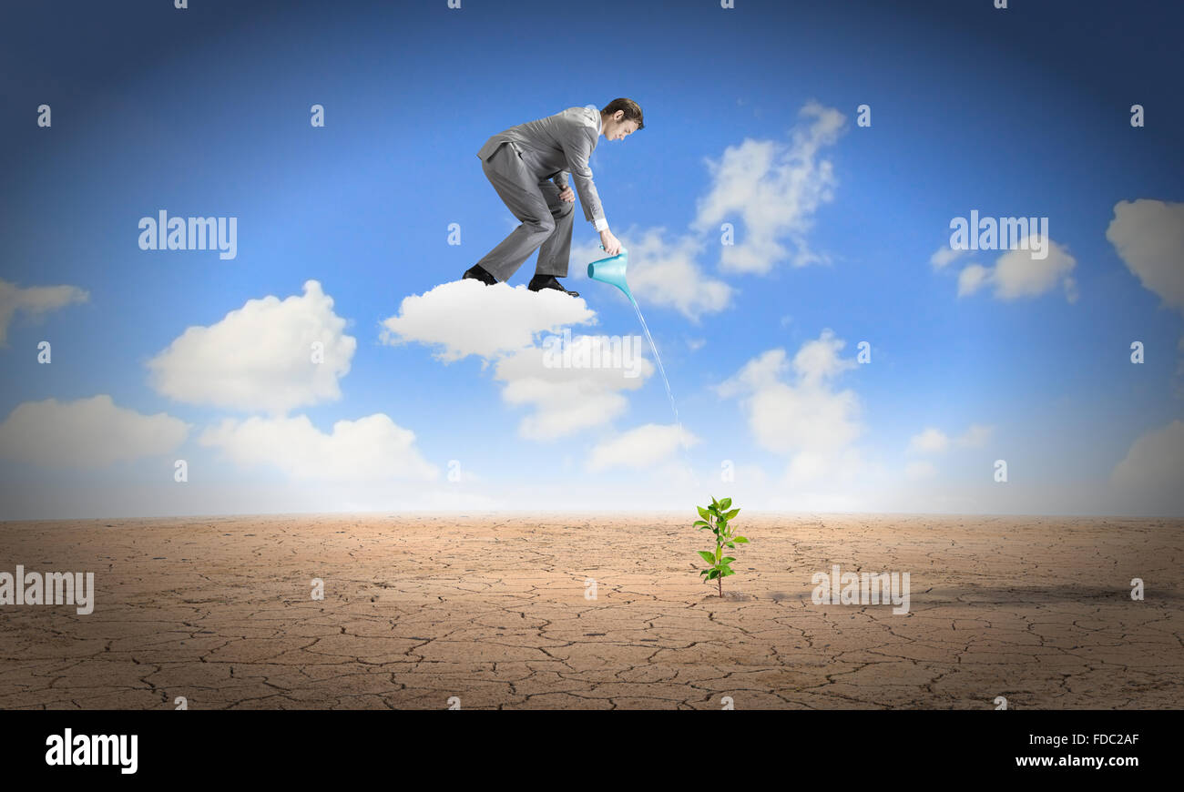 Young businessman standing on cloud and watering sprout Stock Photo - Alamy