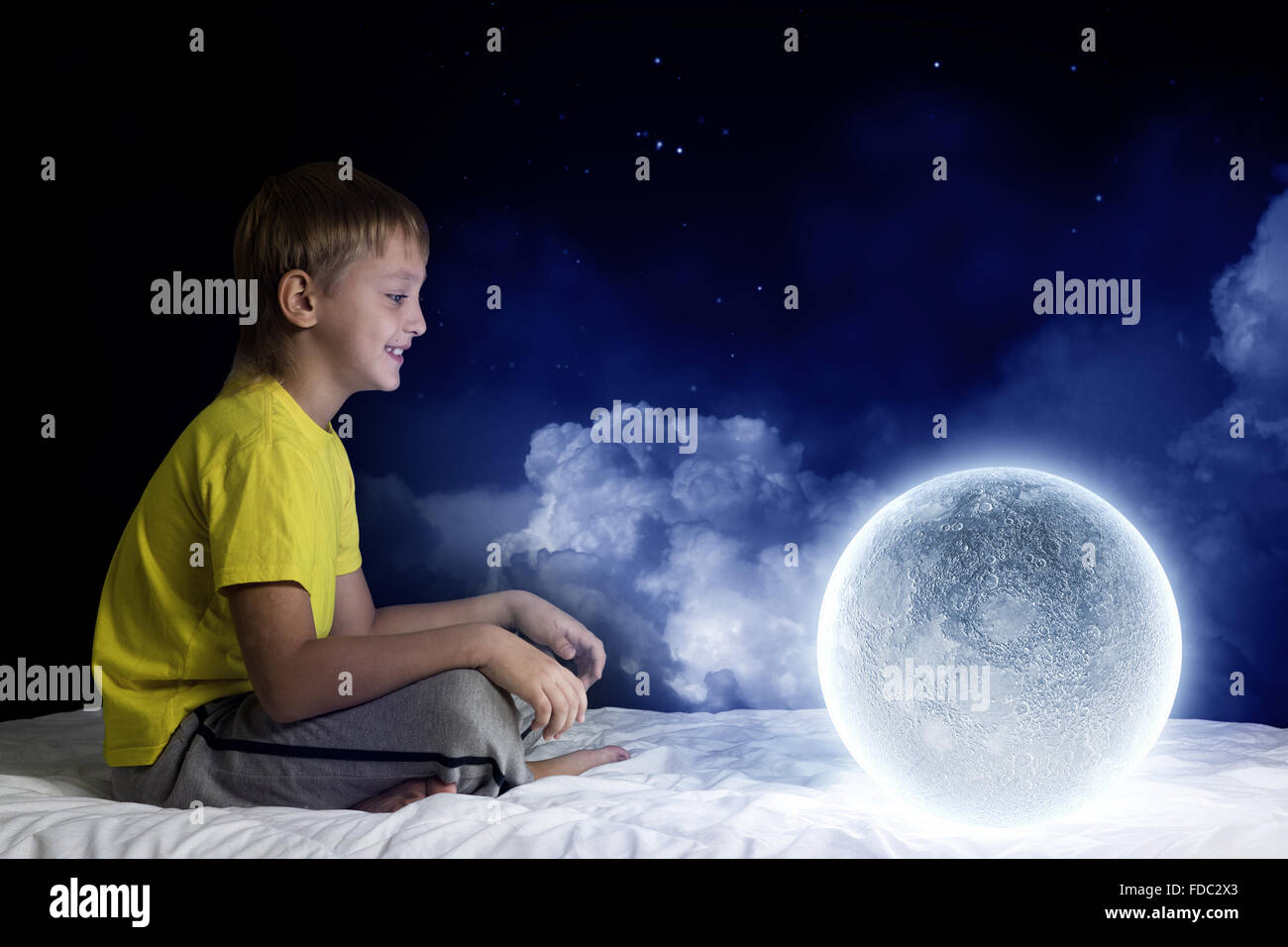 Cute boy sitting in bed with moon planet Stock Photo - Alamy
