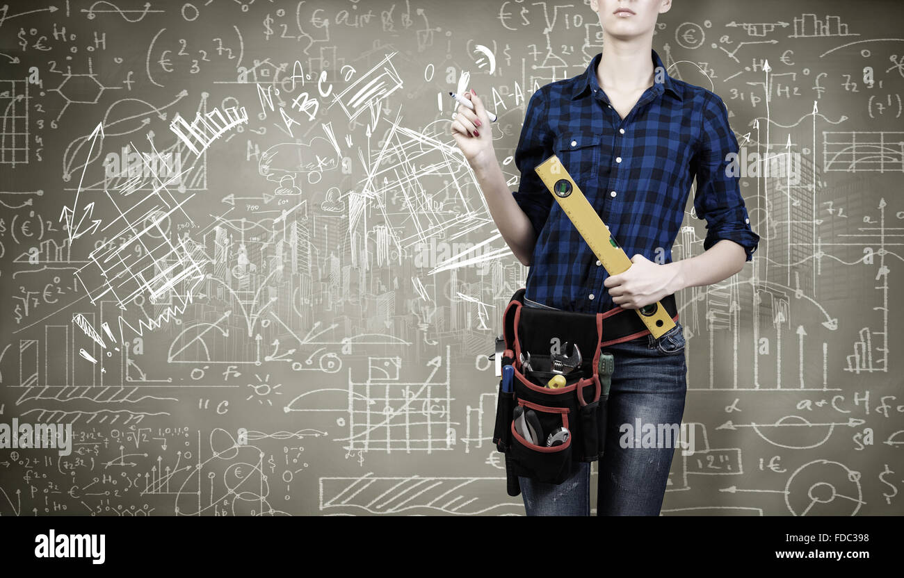 Close up of woman mechanic with ruler in hand against city background ...