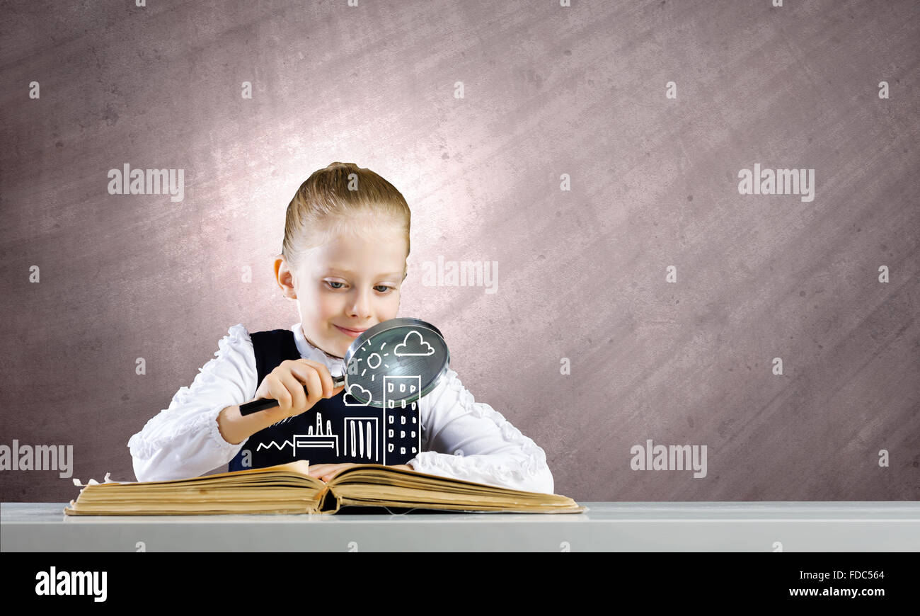 Schoolgirl examining opened book with magnifying glass Stock Photo - Alamy