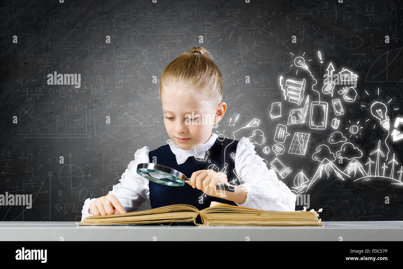 Schoolgirl examining opened book with magnifying glass Stock Photo - Alamy