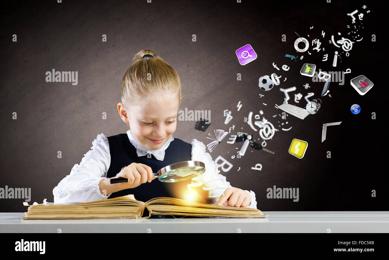 Schoolgirl examining opened book with magnifying glass Stock Photo - Alamy