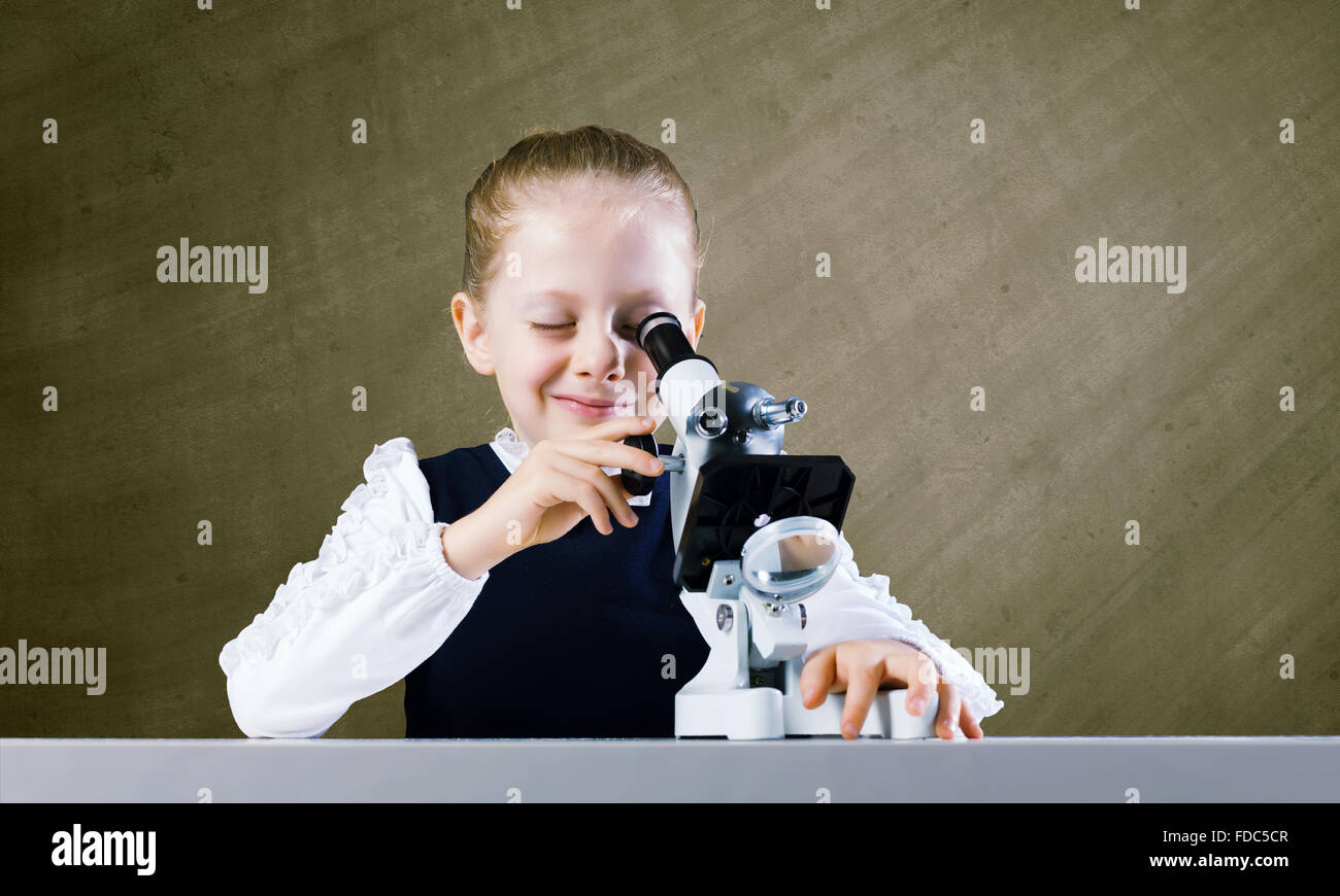 Cute school girl with microscope in classroom Stock Photo - Alamy