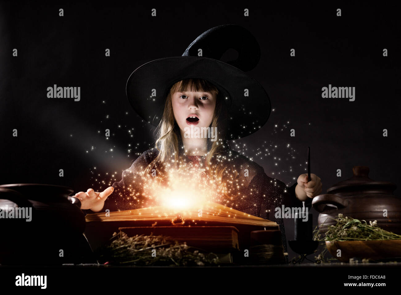 Little Halloween witch reading conjure from magic book Stock Photo - Alamy