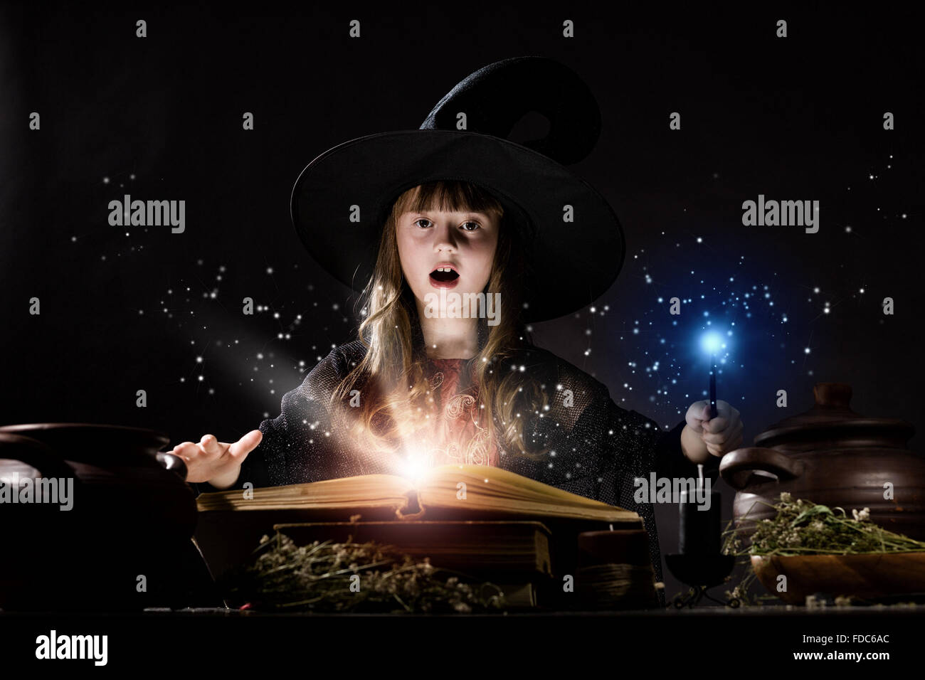 Little Halloween witch reading conjure from magic book Stock Photo - Alamy
