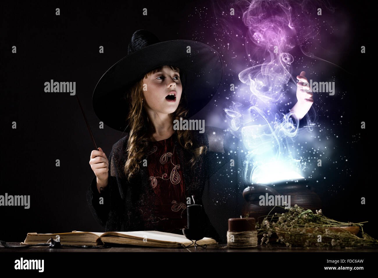 Little Halloween witch reading conjure above pot Stock Photo - Alamy
