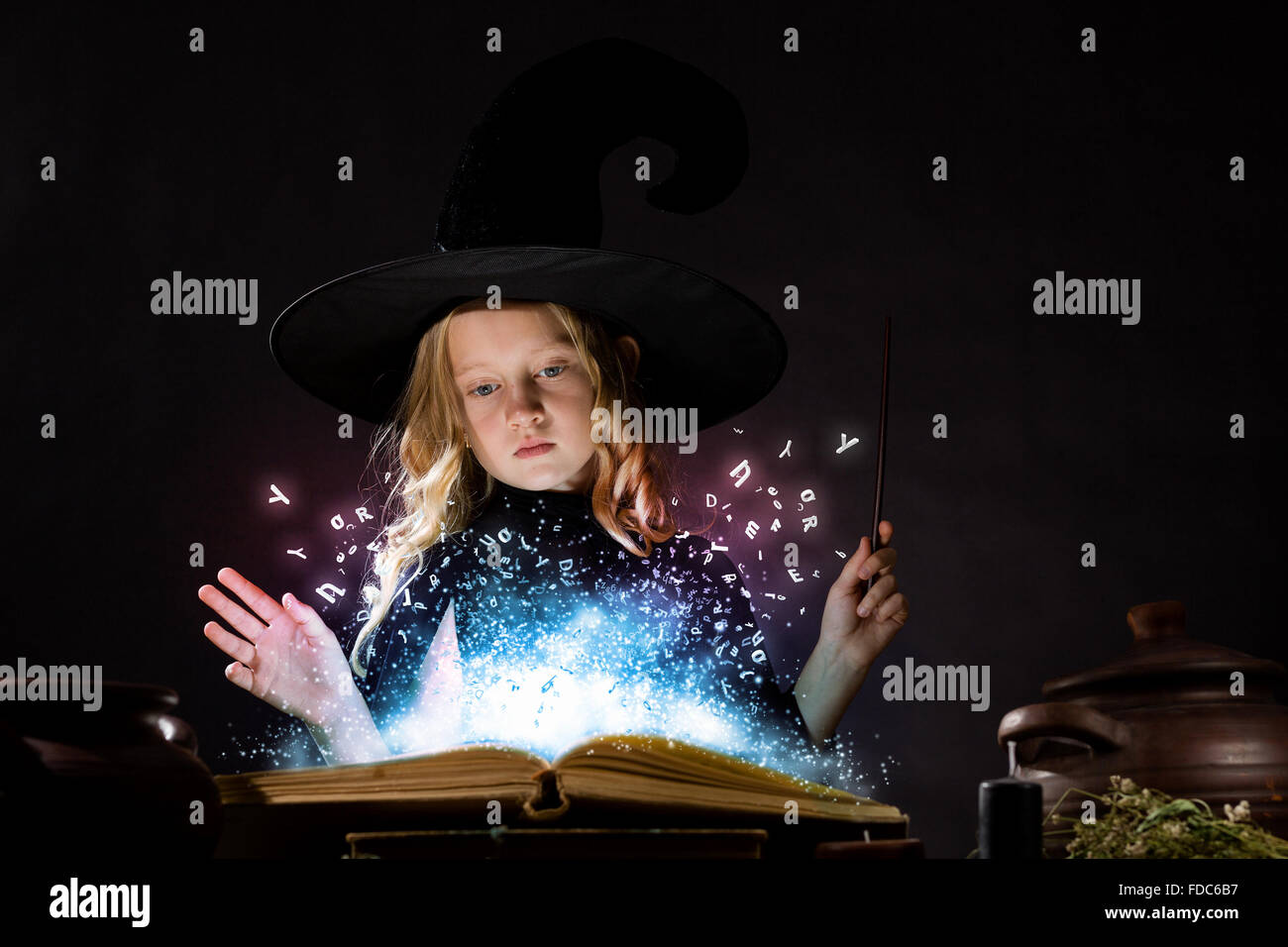 Little Halloween witch reading conjure from magic book Stock Photo - Alamy