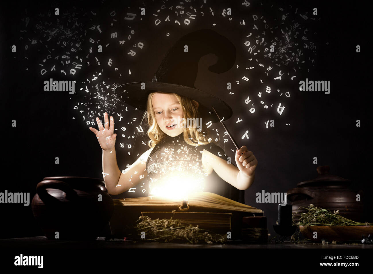 Little Halloween witch reading conjure from magic book Stock Photo - Alamy