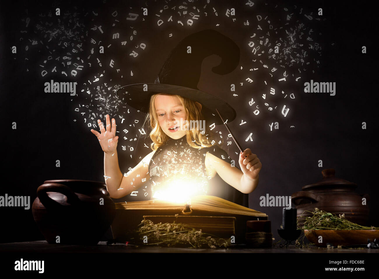 Little Halloween witch reading conjure from magic book Stock Photo - Alamy