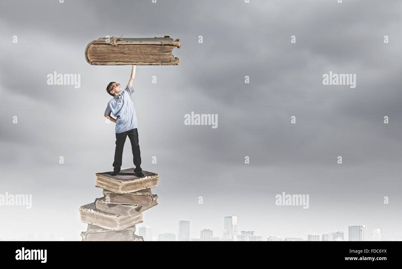 Young man holding huge book above head on one hand Stock Photo - Alamy