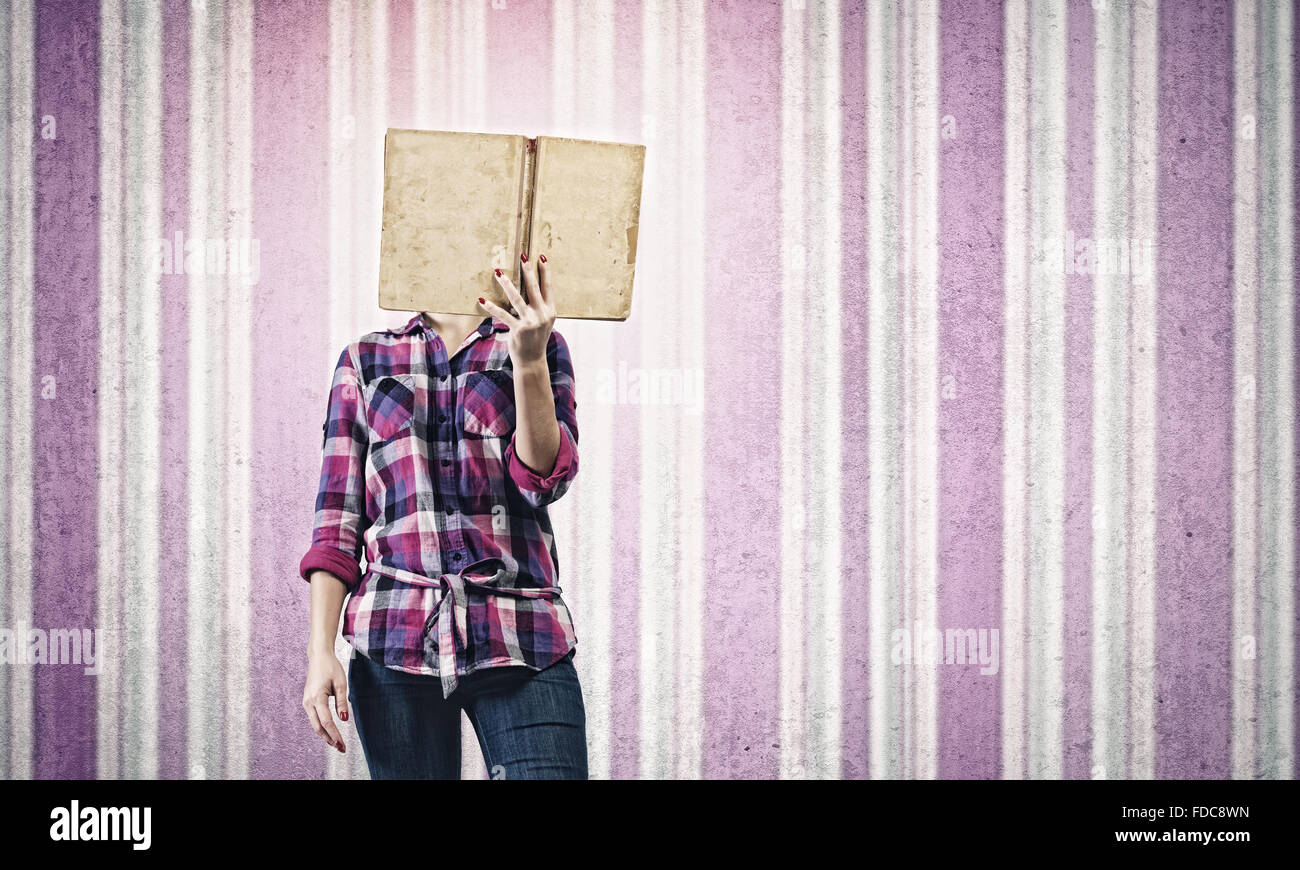 Young woman in casual hiding face behind reading Stock Photo - Alamy