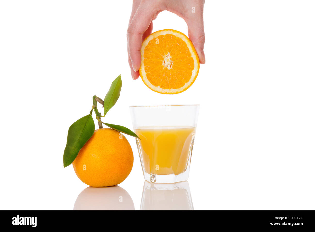Freshly squeezed orange juice. Female hand squeezing orange into a ...
