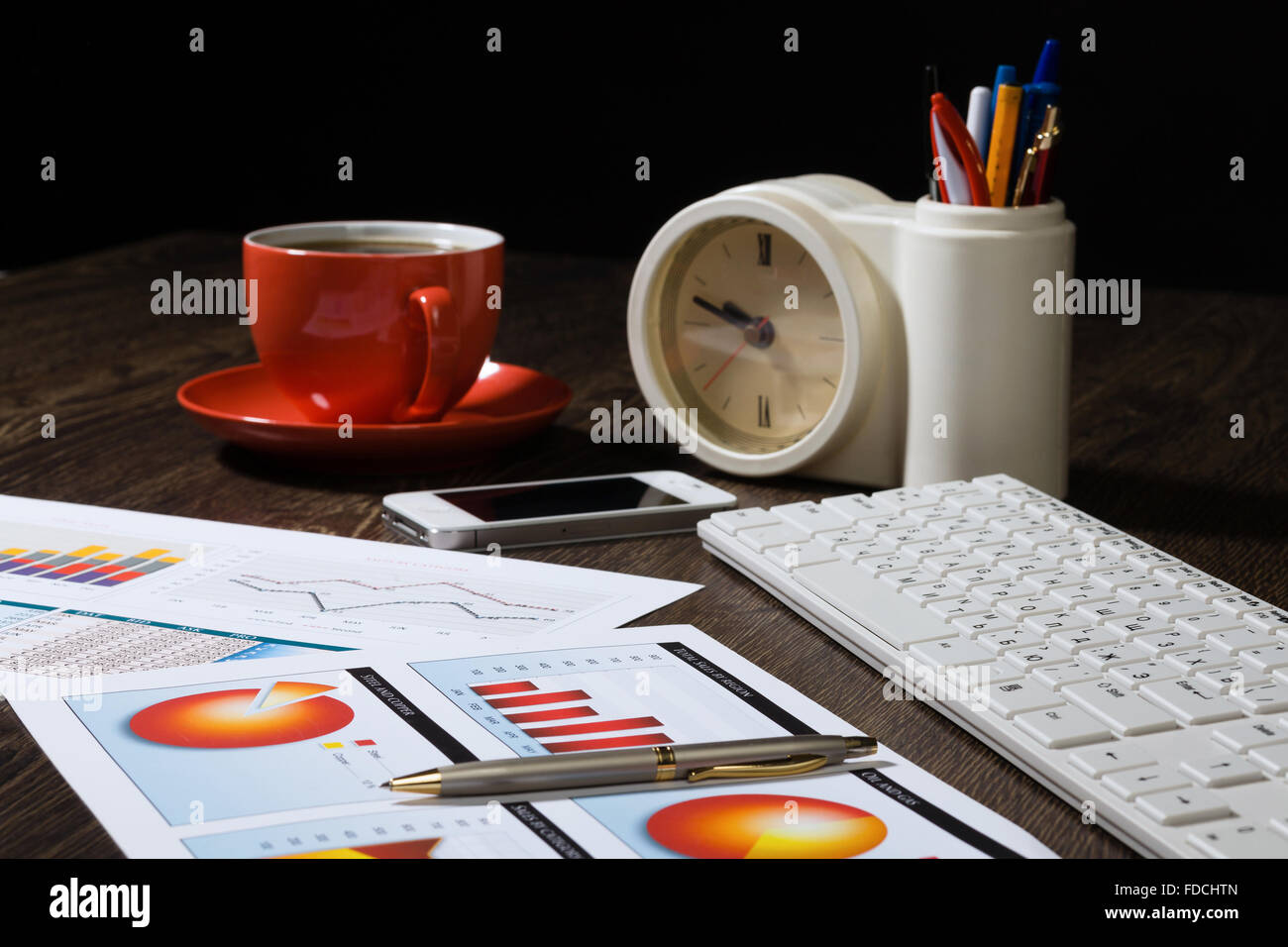 Workplace with keyboard cup of coffee and graphs Stock Photo - Alamy