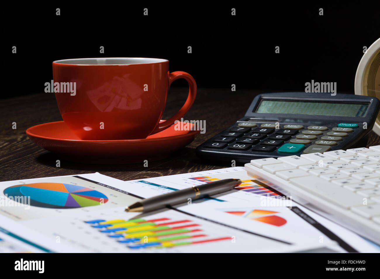 Workplace with keyboard cup of coffee and graphs Stock Photo - Alamy