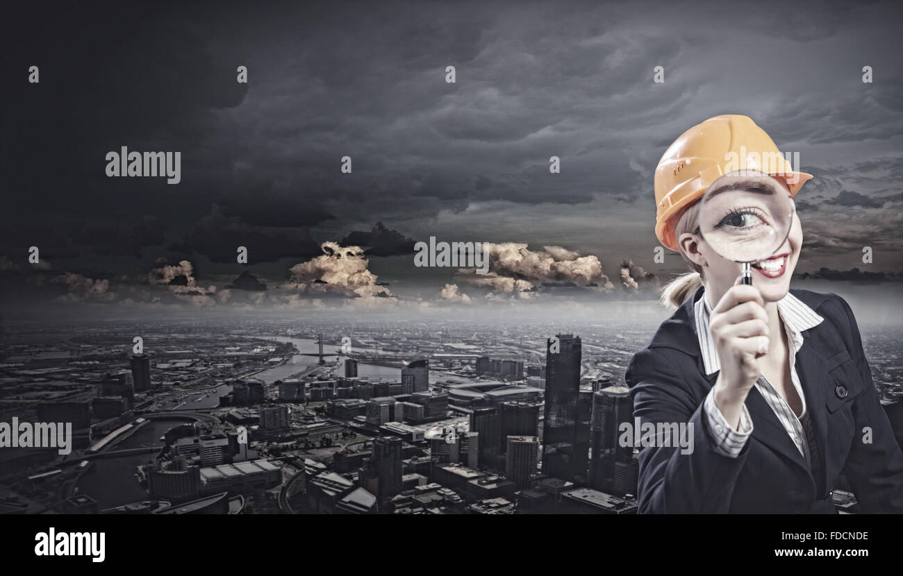 Young woman engineer looking in magnifying glass Stock Photo - Alamy