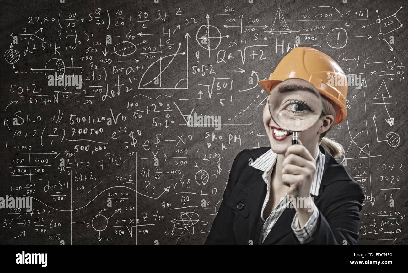 Young woman engineer looking in magnifying glass Stock Photo - Alamy