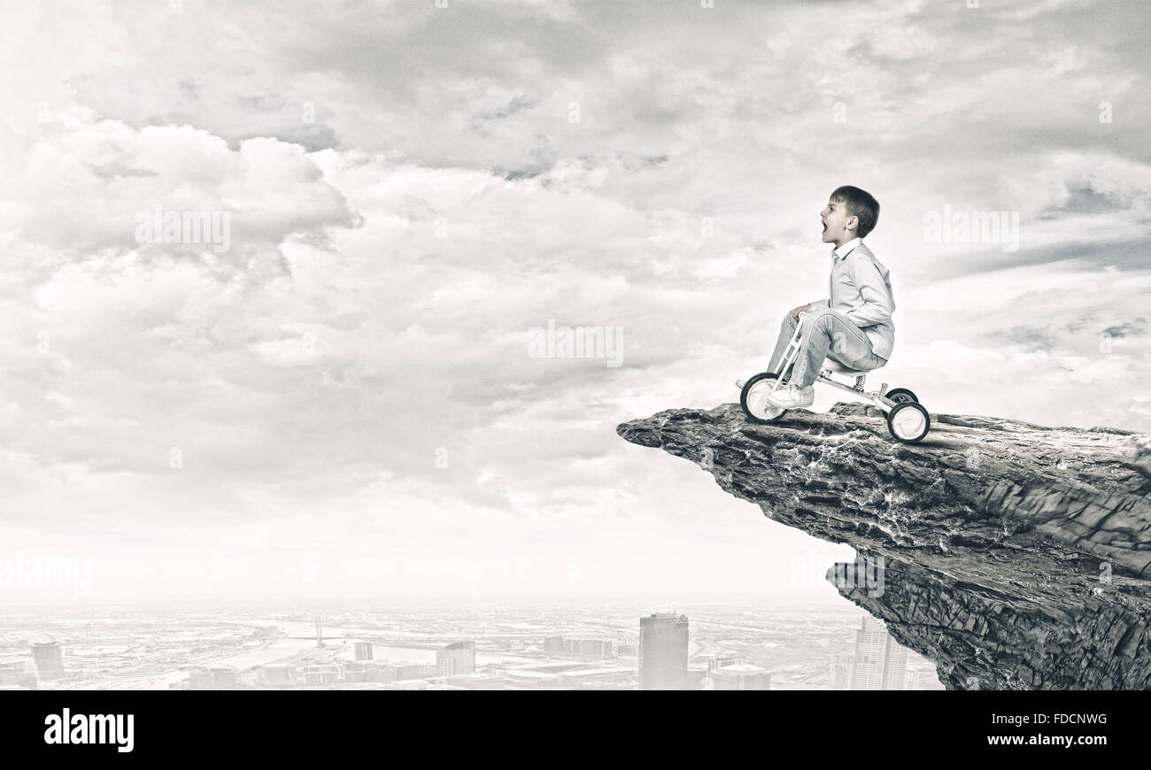 Little joyful cute boy riding tricycle on cliff edge Stock Photo - Alamy