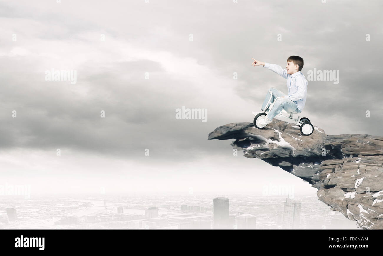 Little joyful cute boy riding tricycle on cliff edge Stock Photo - Alamy