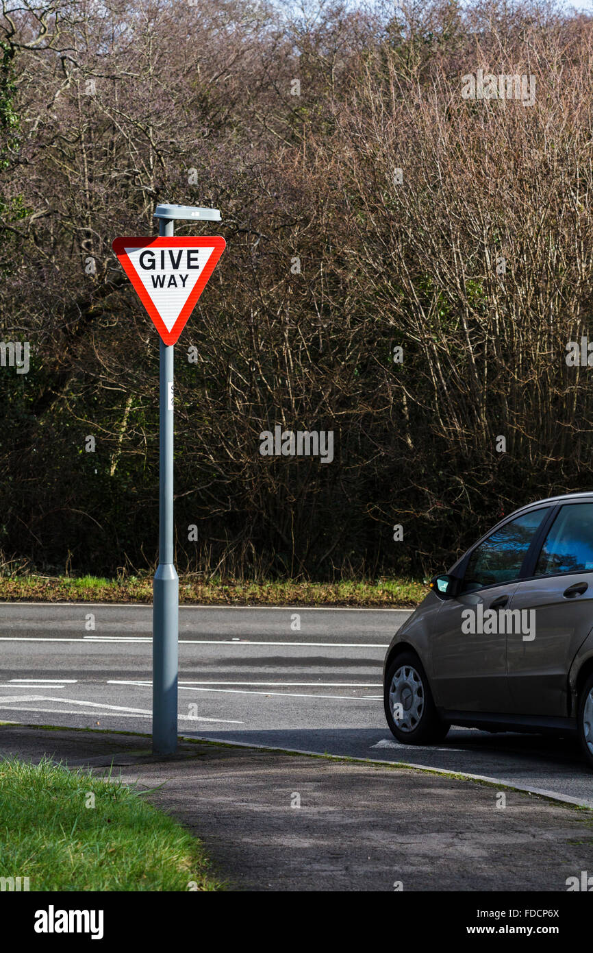 A Give Way road sign with a stationary car stopped at the junction ...