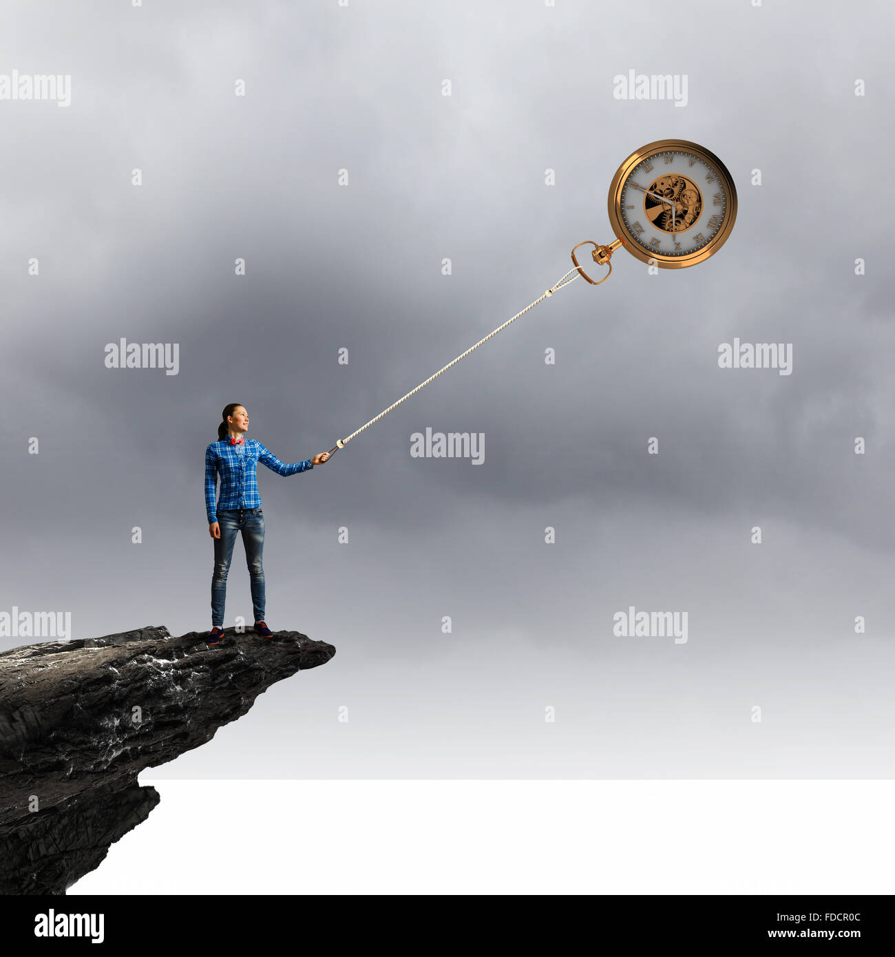 Young woman in casual catching clock with rope Stock Photo - Alamy