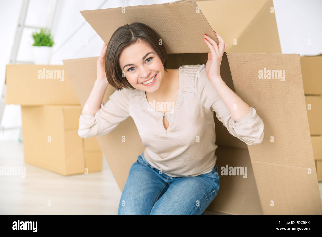 Positive charming girl hiding under the box Stock Photo - Alamy