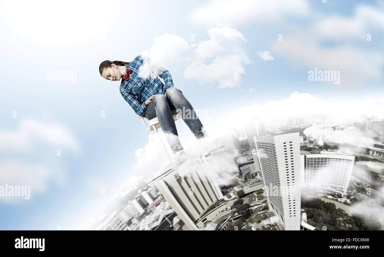 Young giant woman sitting on chair above modern city Stock Photo - Alamy