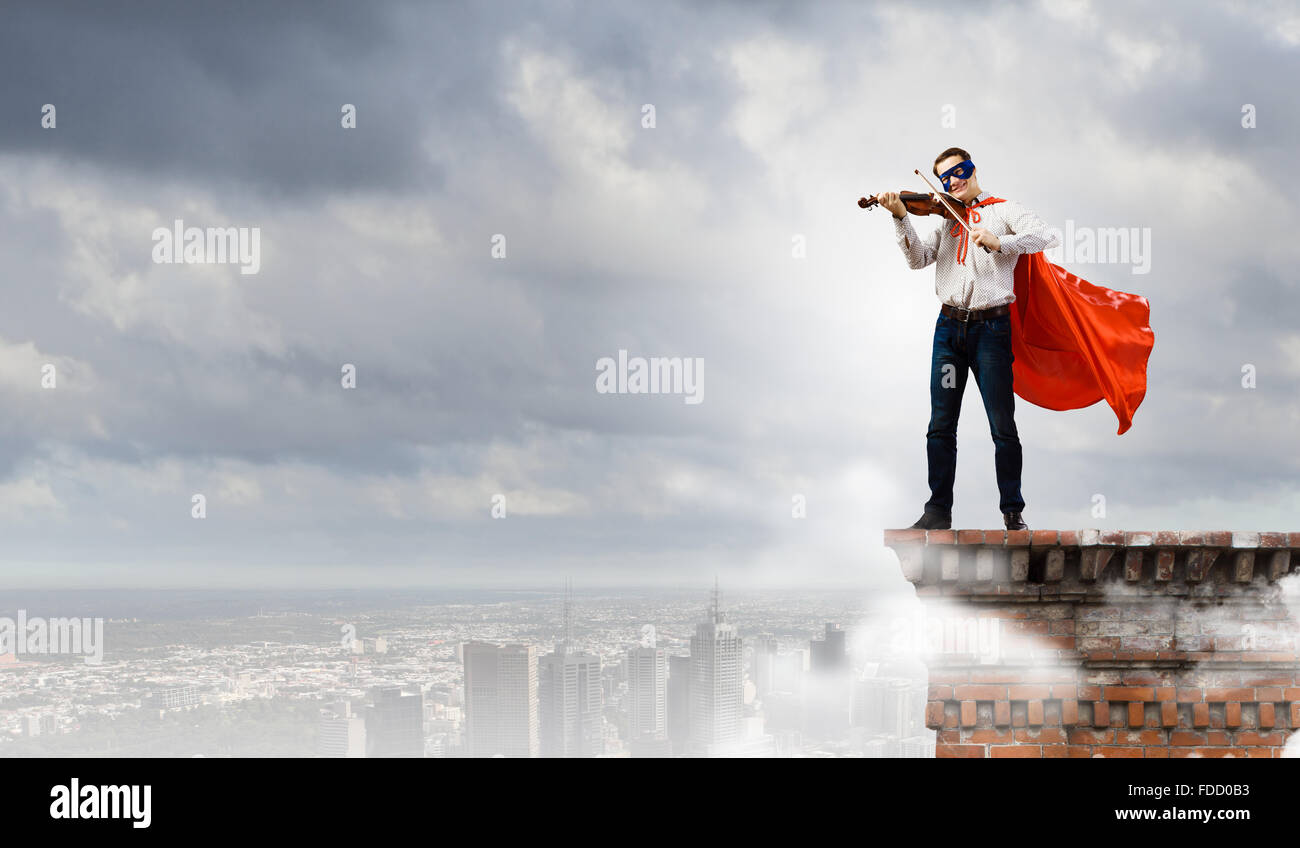 Young man in superhero costume playing violin Stock Photo - Alamy