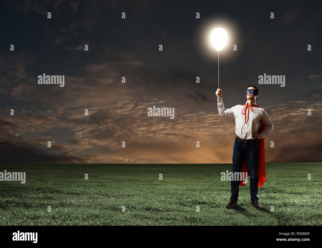 Young man in superhero costume holding balloon in hand Stock Photo - Alamy