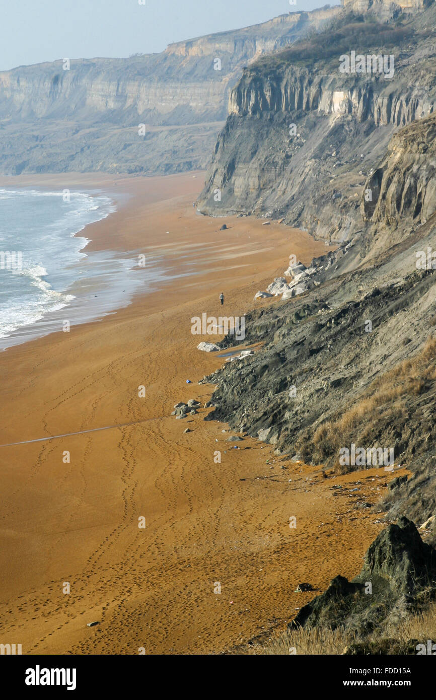 a solitary human figure walks on a deserted red sand beach cliff cliffs ...