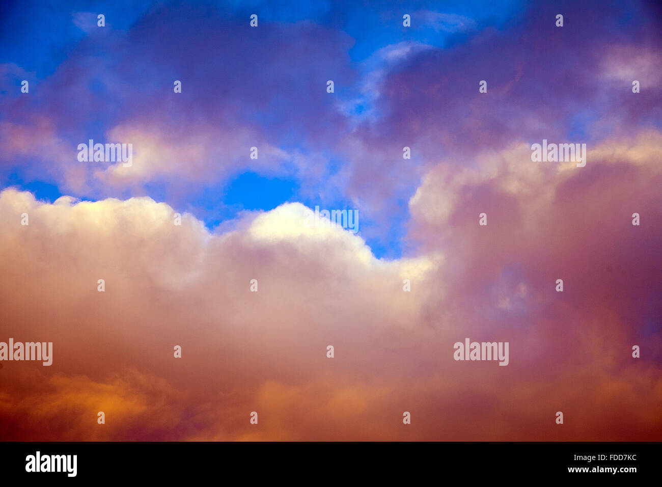 Dramatic sky of low hanging coloured clouds against a dark blue sky ...