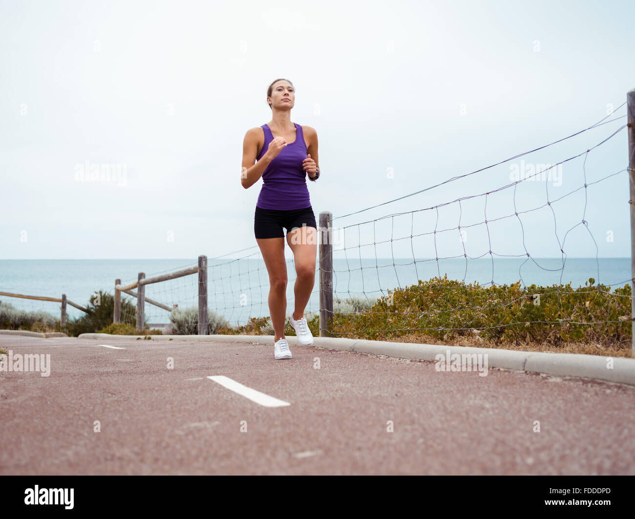 Sporty young woman running on the sea coast Stock Photo - Alamy