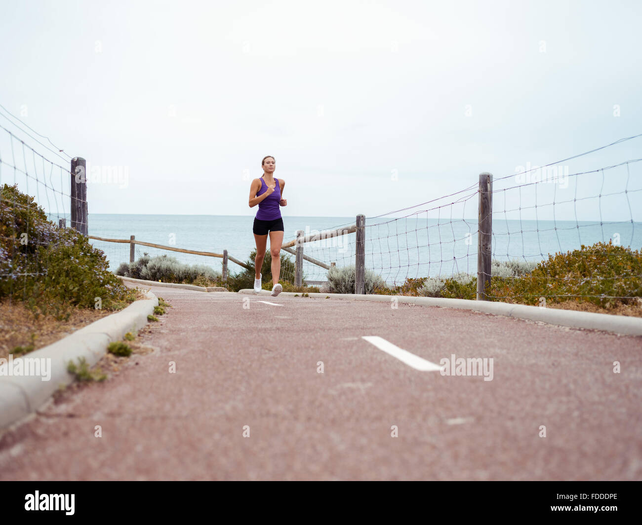 Sporty young woman running on the sea coast Stock Photo - Alamy