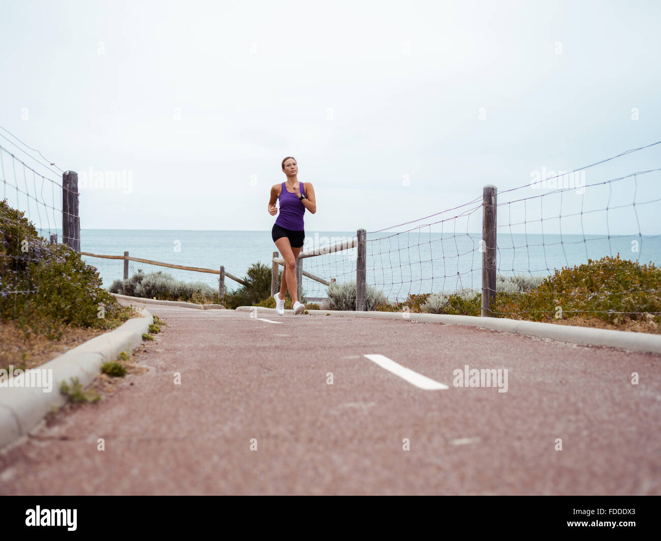 Sporty young woman running on the sea coast Stock Photo - Alamy