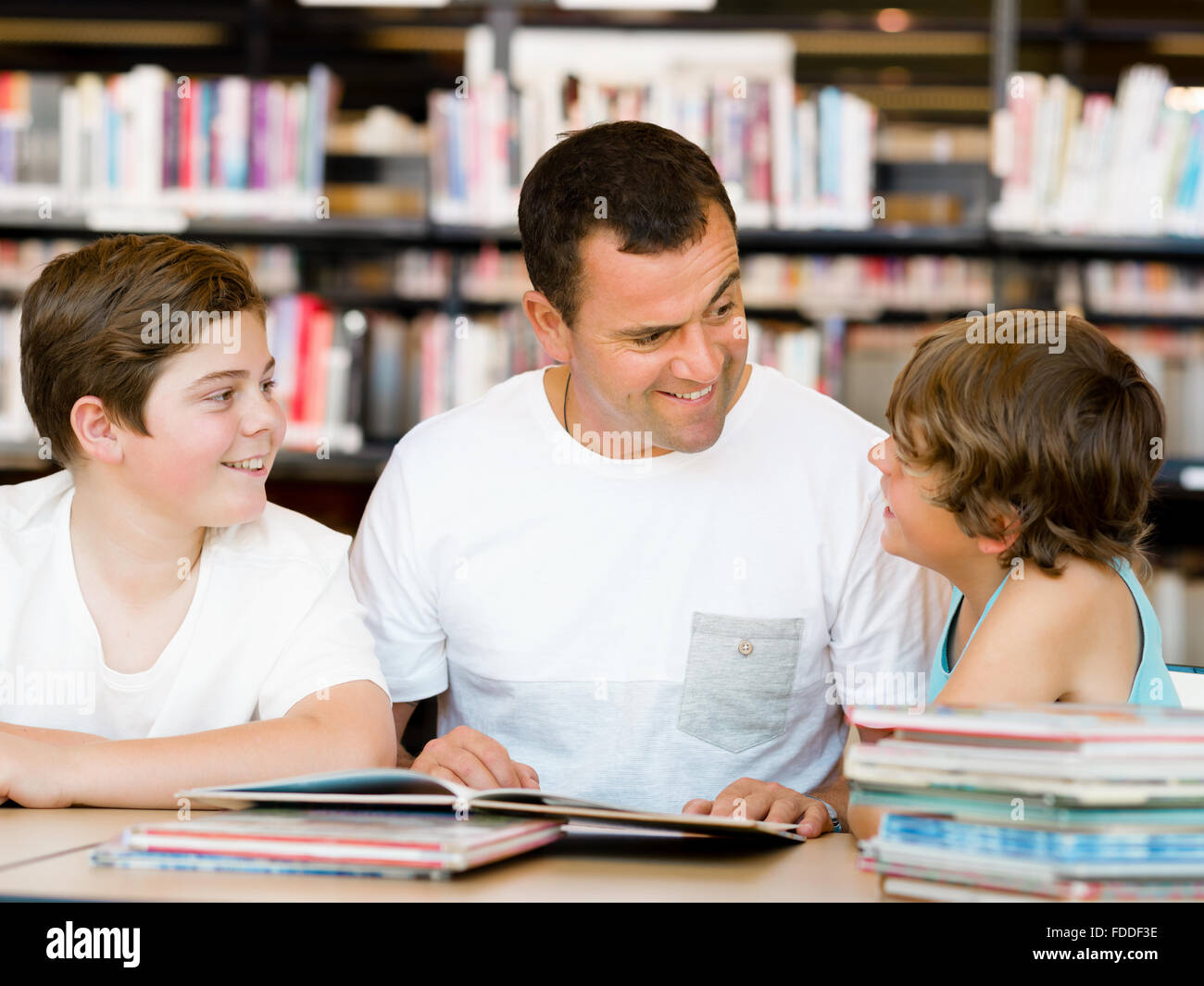 Father with sons in library with books Stock Photo - Alamy