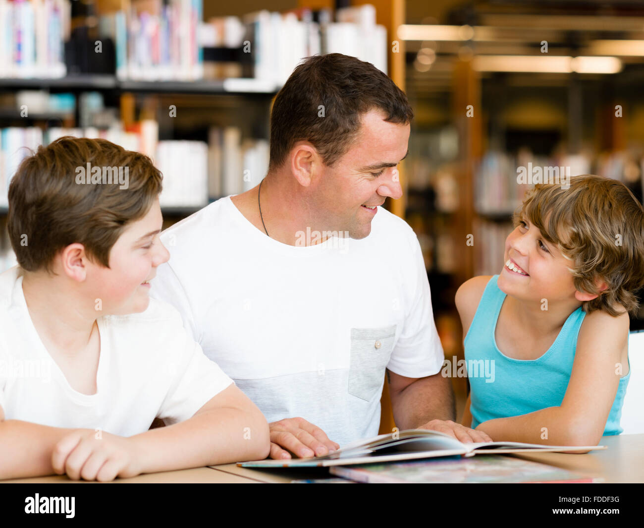 Father with sons in library with books Stock Photo - Alamy