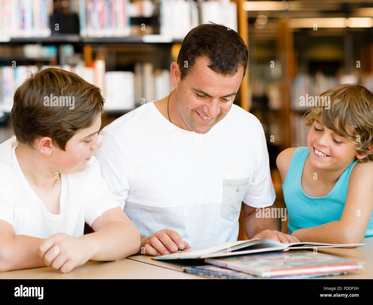 Father with sons in library with books Stock Photo - Alamy