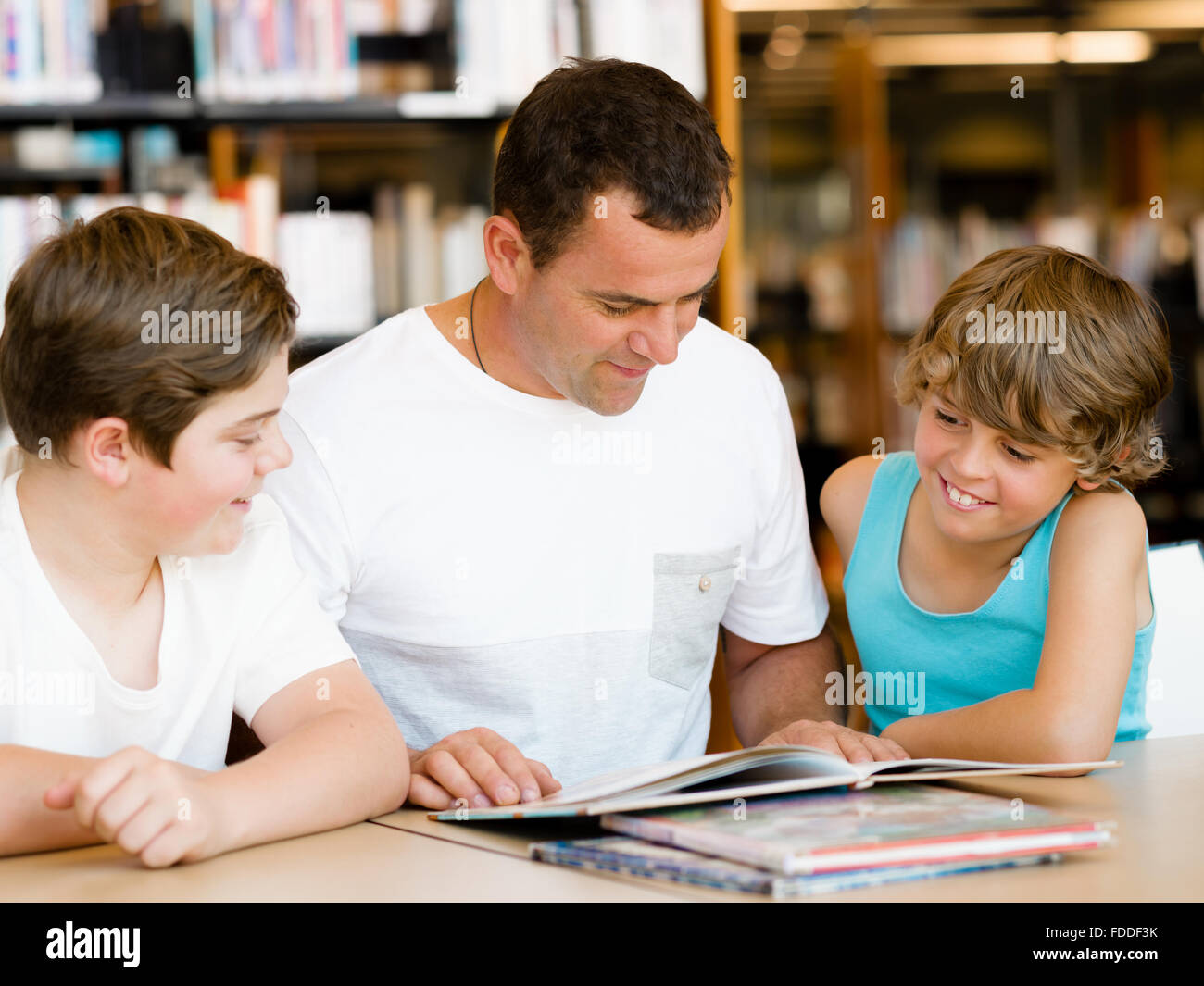 Father with sons in library with books Stock Photo - Alamy