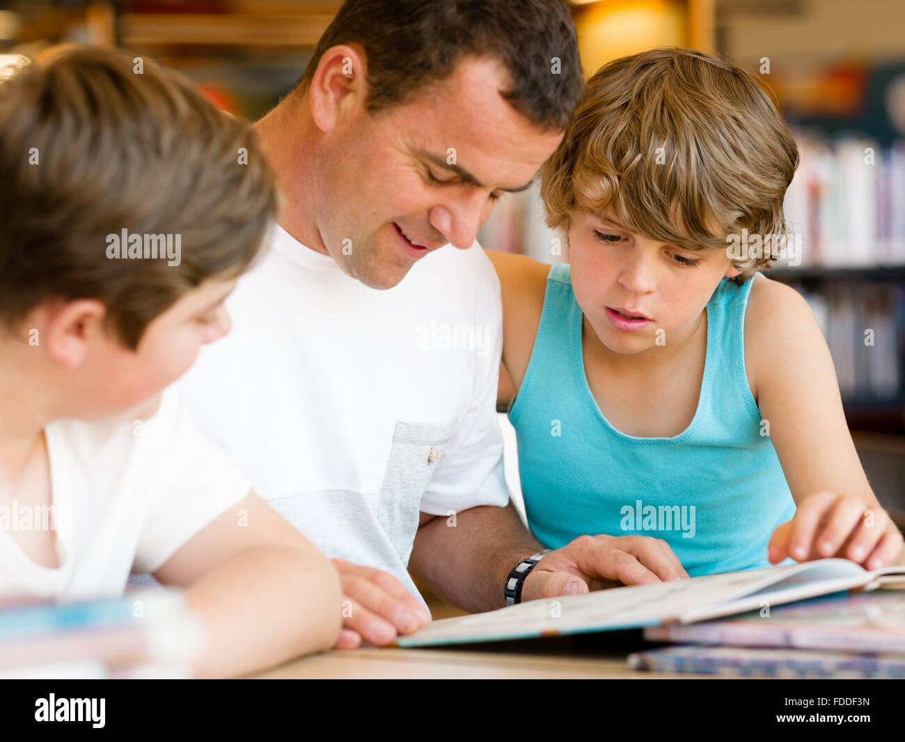 Father with sons in library with books Stock Photo - Alamy