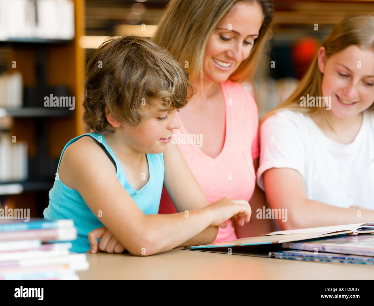 Mother with kids in library with books Stock Photo - Alamy