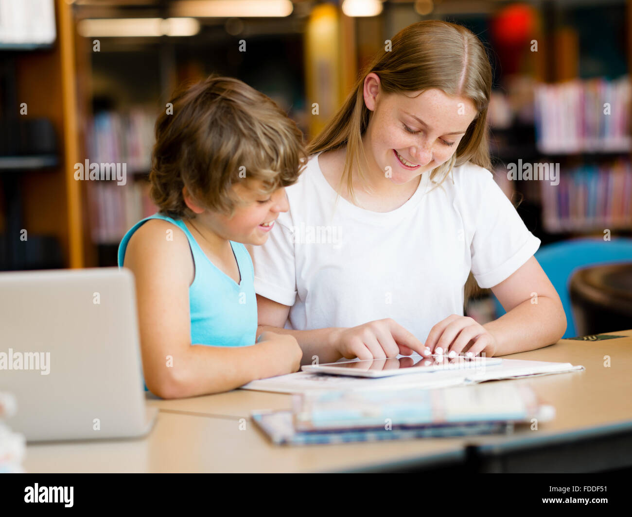 Teenage girl and her brother with books studying in library Stock Photo ...