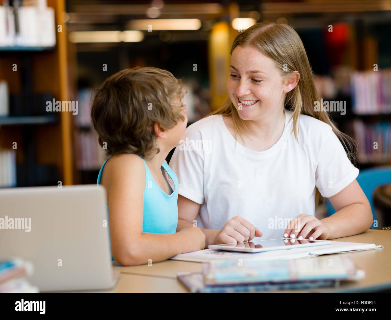 Teenage girl and her brother with books studying in library Stock Photo ...