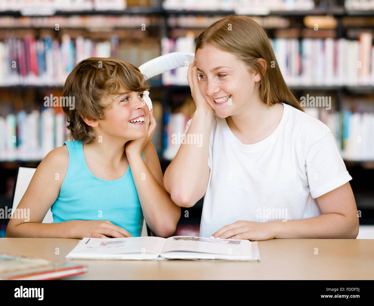 Teenage girl and her brother with books in library Stock Photo - Alamy
