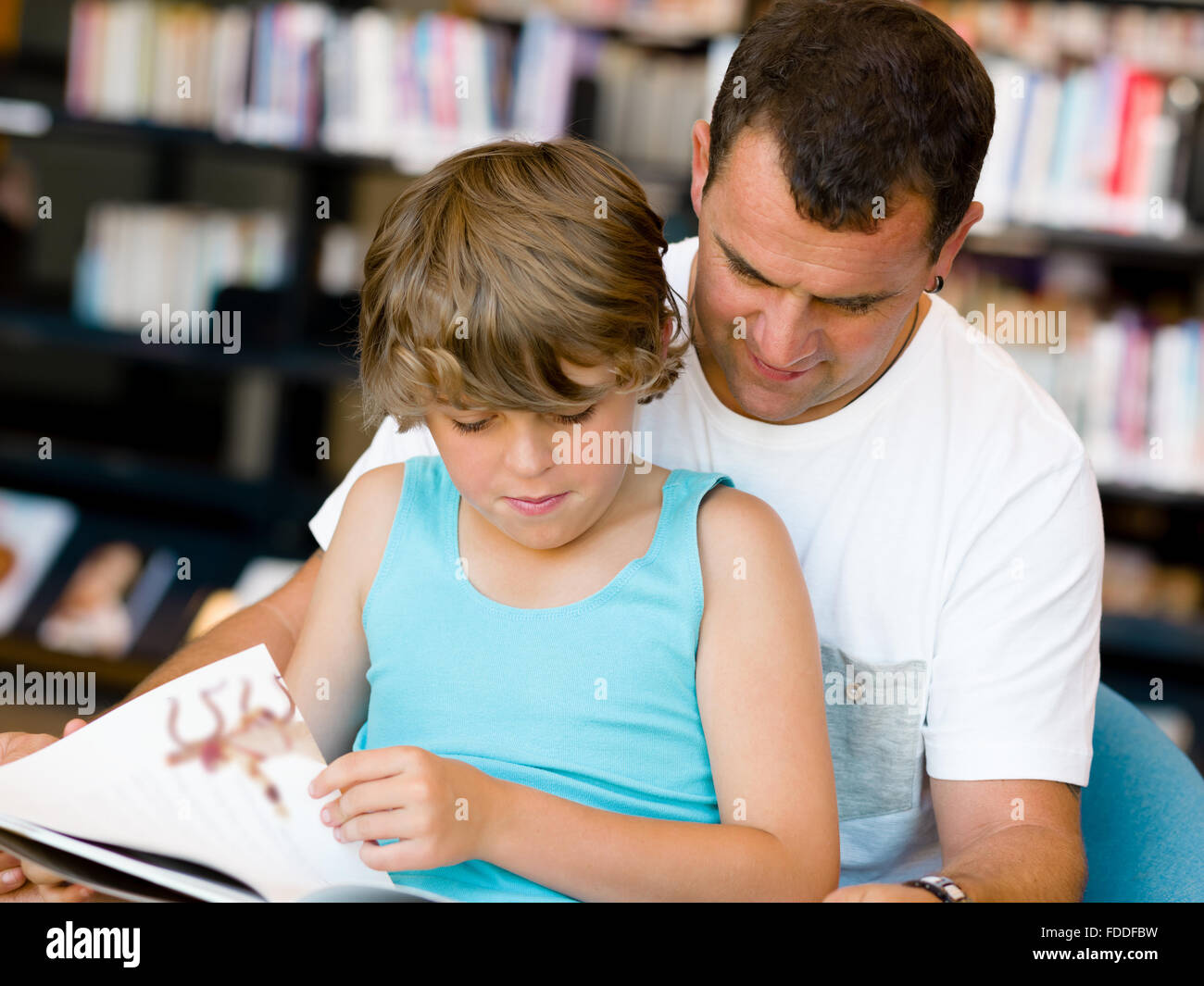 Father with son in library with books Stock Photo - Alamy