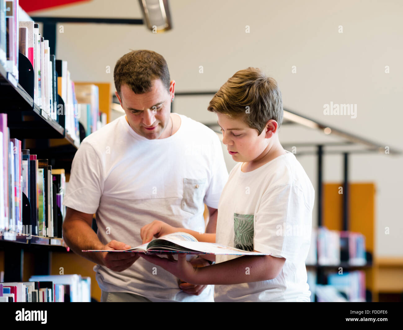 Boy and his father in library choosing books Stock Photo - Alamy