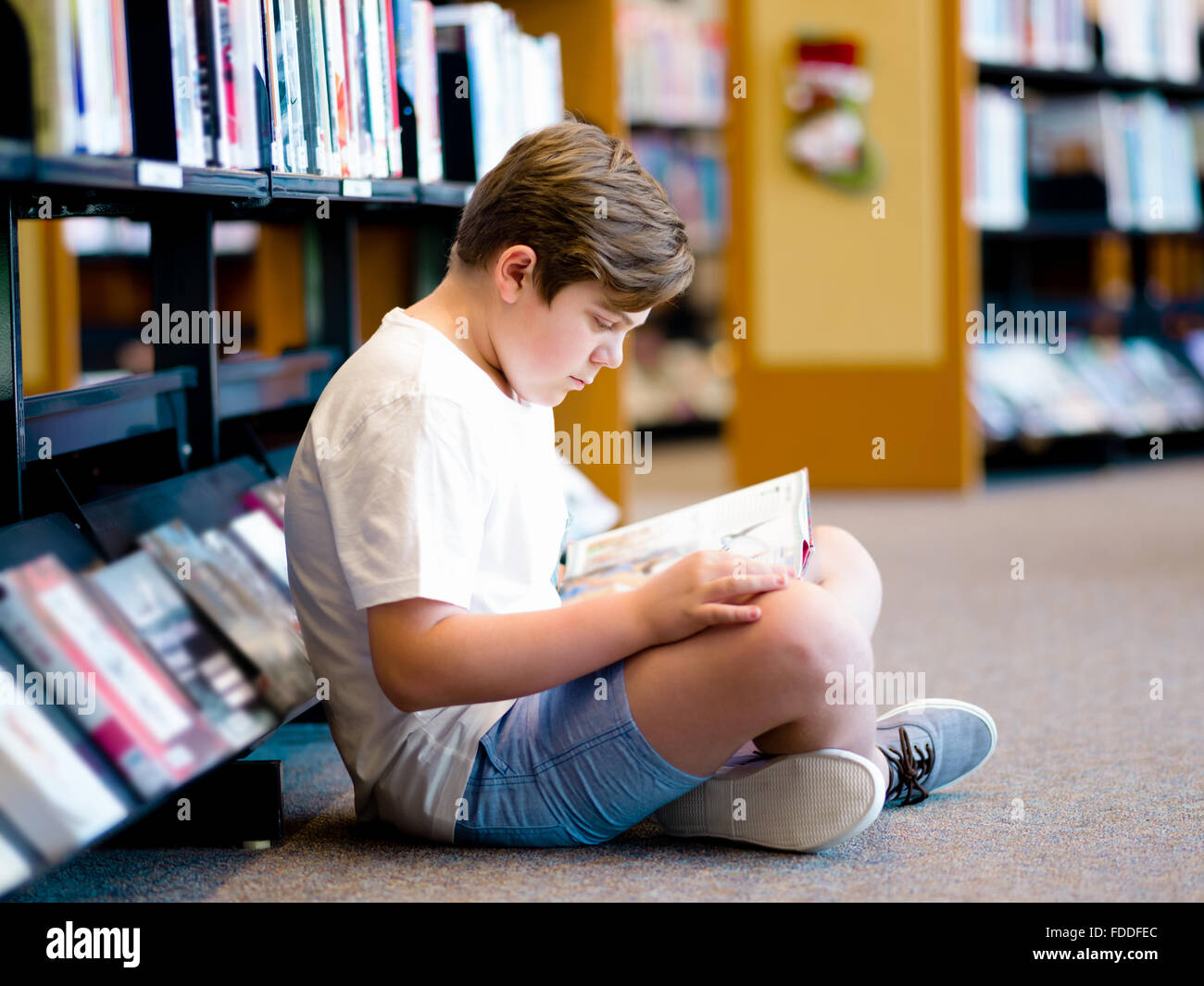 Boy in library with books Stock Photo - Alamy